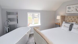 Quarto com uma cama grande, banheira, janela e mesa de cabeceira com abajur.