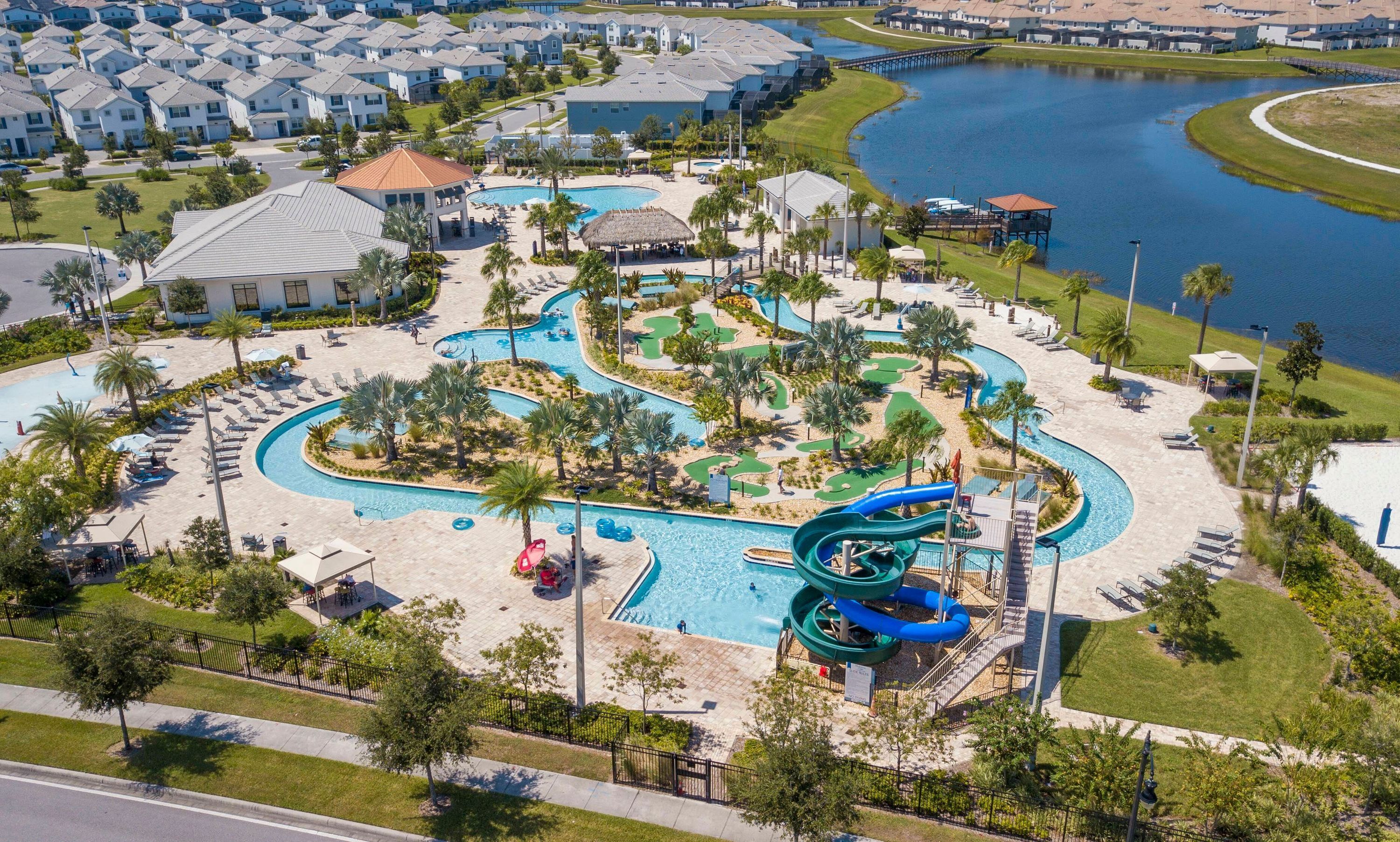 Vista aérea de um resort com área de piscina central, várias escorregas aquáticas e um lago.