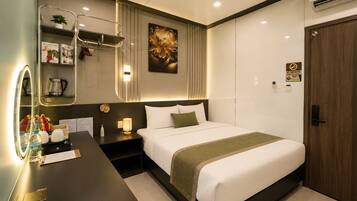 Quarto de hotel moderno com uma cama grande, mesa de cabeceira com abajur, espelho e uma pequena estante com objetos decorativos.