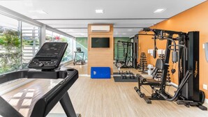 Academia moderna com equipamentos de cardio, máquinas de peso e esteira.