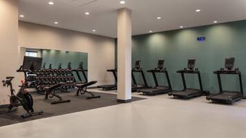 Uma academia com esteiras, halteres e bicicletas ergométricas.