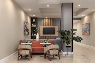 Uma sala de estar moderna com um sofá, duas poltronas listradas, uma mesa de centro, uma TV de tela plana, objetos decorativos e uma planta grande.
