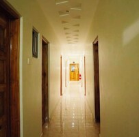 Um corredor com piso de azulejos, portas de madeira e um extintor de incêndio na parede.
