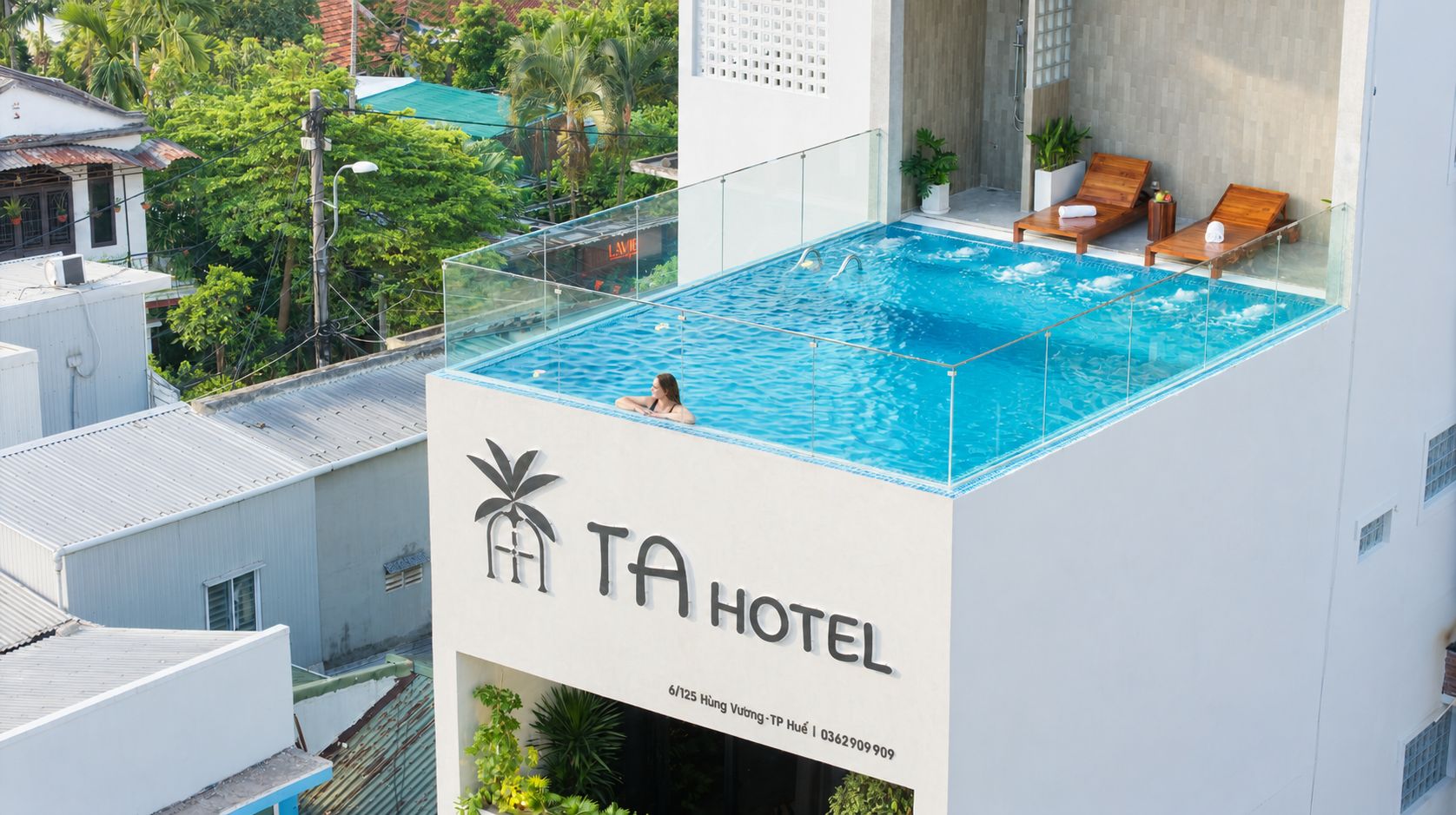 Piscina no terraço com espreguiçadeiras e uma pessoa nadando.
