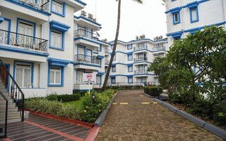 Um edifício residencial com várias varandas, placa indicando zona de proibição de buzinas e um caminho pavimentado.