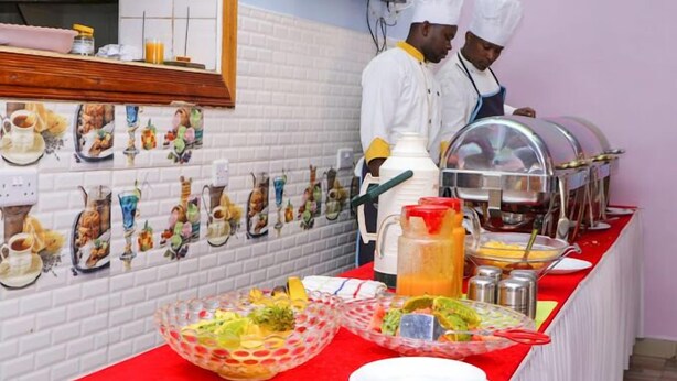 Uma mesa de buffet com diversos alimentos e um chef preparando refeições.