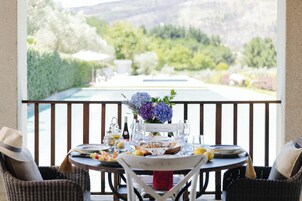 Mesa de jantar posta ao ar livre, com vista para uma piscina e vegetação.
