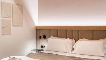 Quarto moderno com teto de madeira, cama com roupa de cama branca e duas mesinhas de cabeceira com toalhas e chinelos.