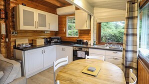 Uma cozinha acolhedora em estilo cabana, com paredes de madeira, armários brancos, uma ilha central e uma mesa de jantar.