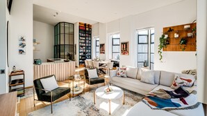 Uma sala de estar moderna com um sofá, poltronas, uma mesa de centro e uma estante de livros.