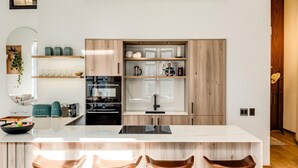 Uma cozinha moderna com uma ilha central, armários de madeira e banquetas de bar.