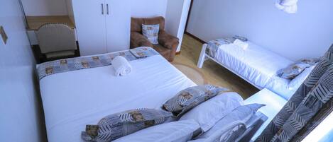 Quarto com uma cama grande, uma cama menor, uma cadeira e um guarda-roupa.