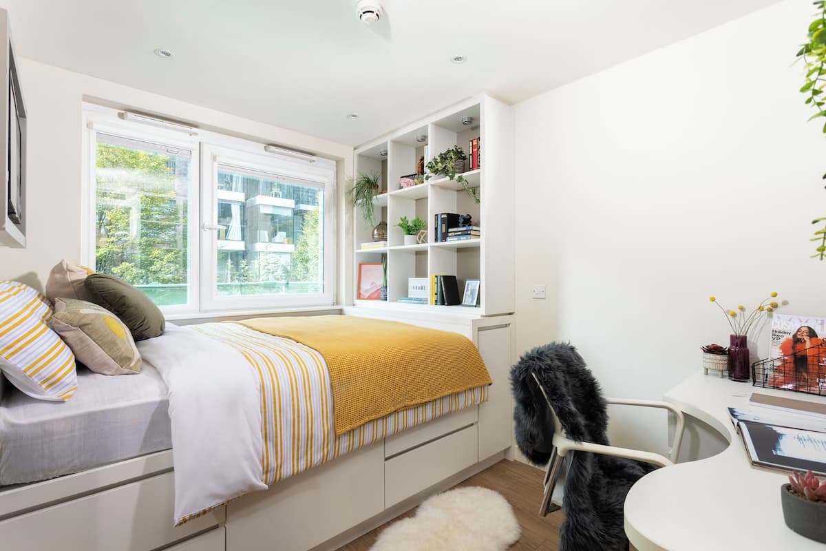 Um quarto moderno com uma cama, uma escrivaninha e uma estante.