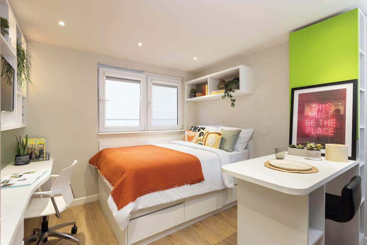 Um quarto moderno com uma cama, escrivaninha e estante.