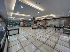 Um hall amplo com piso de mármore, área de estar e balcão de recepção.