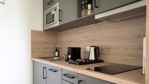 Uma cozinha moderna com bancada de madeira, micro-ondas embutido, máquina de café e chaleira.