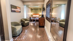 Quarto de hotel com cama, escrivaninha, cadeira e sofá.