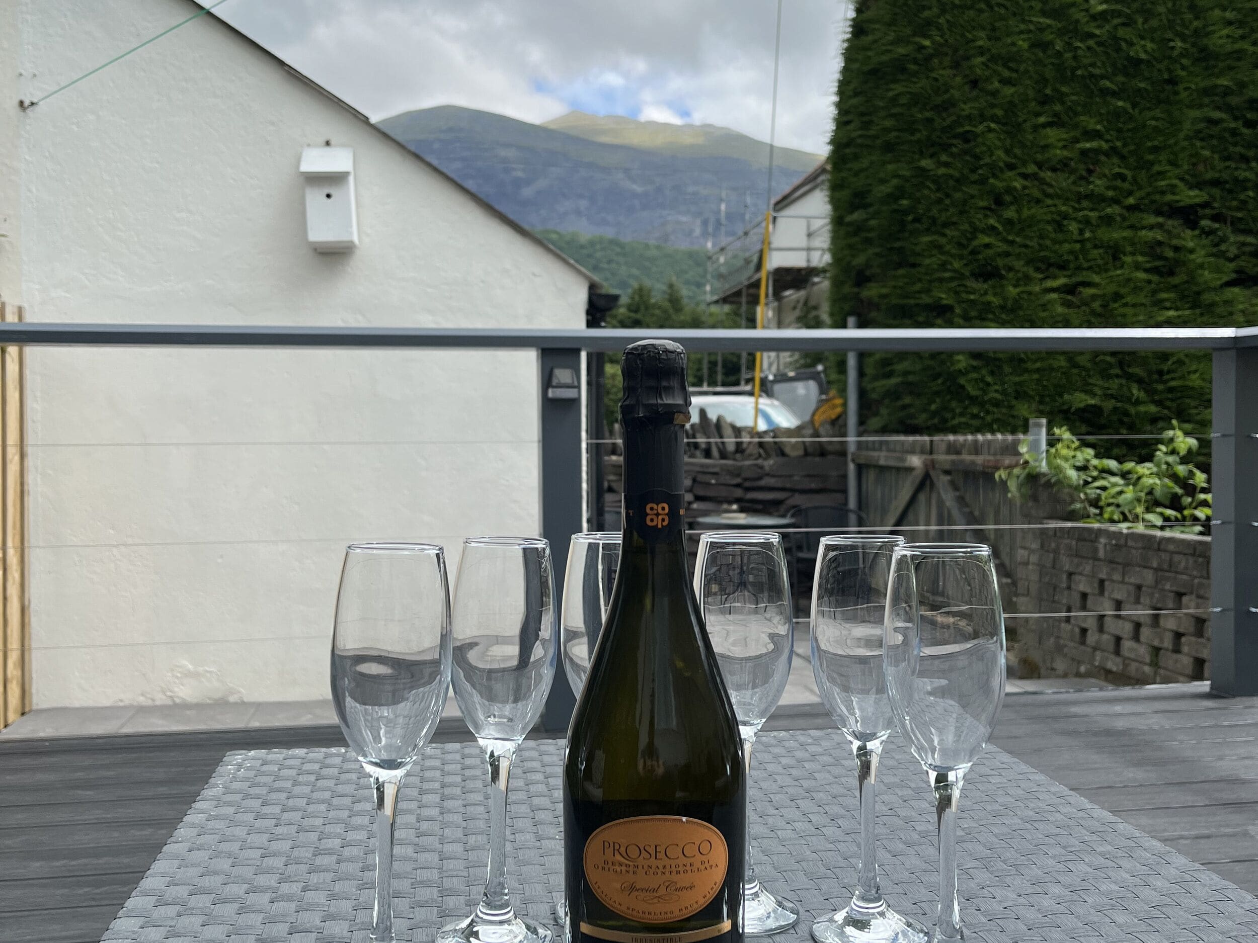 Uma garrafa de vinho prosecco sobre uma mesa com vários copos de vinho vazios.