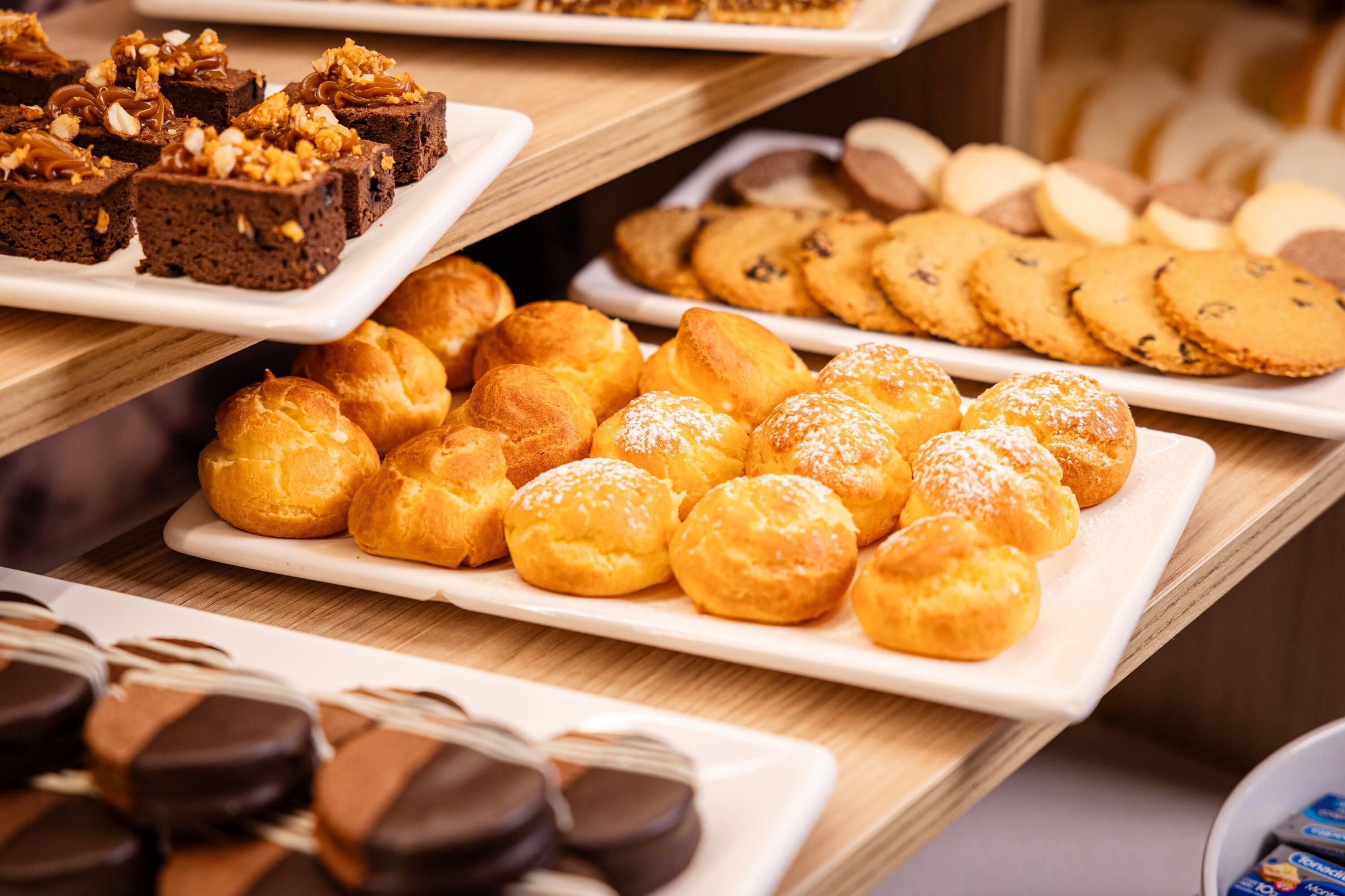 Buffet com diversos produtos de panificação, incluindo doces, bolachas e brownies.