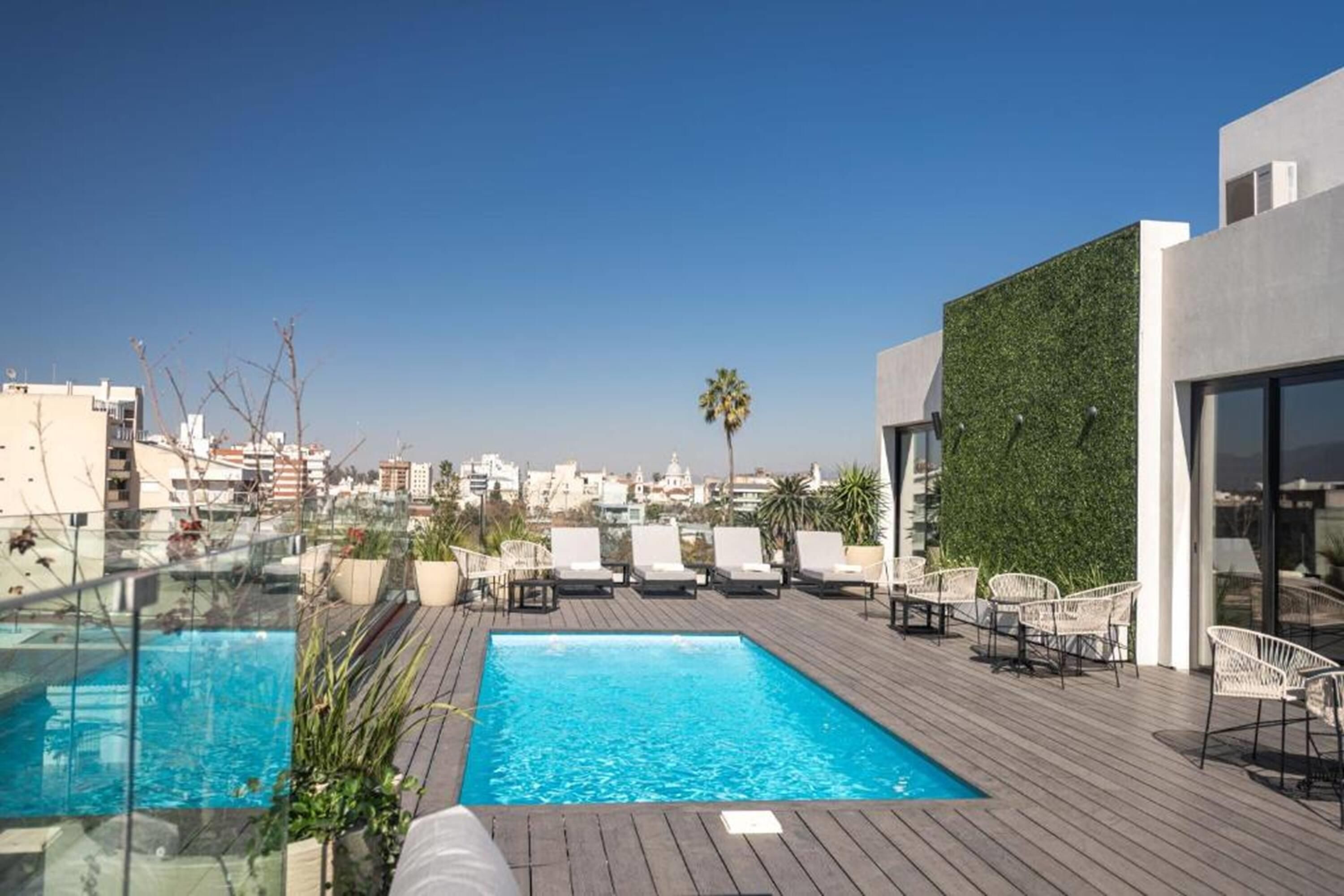 Área de piscina no terraço com espreguiçadeiras e vista da cidade.