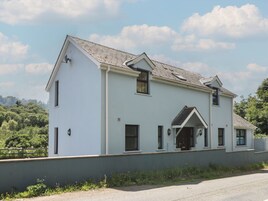 Uma casa de dois andares com telhado empena, varanda frontal e garagem.