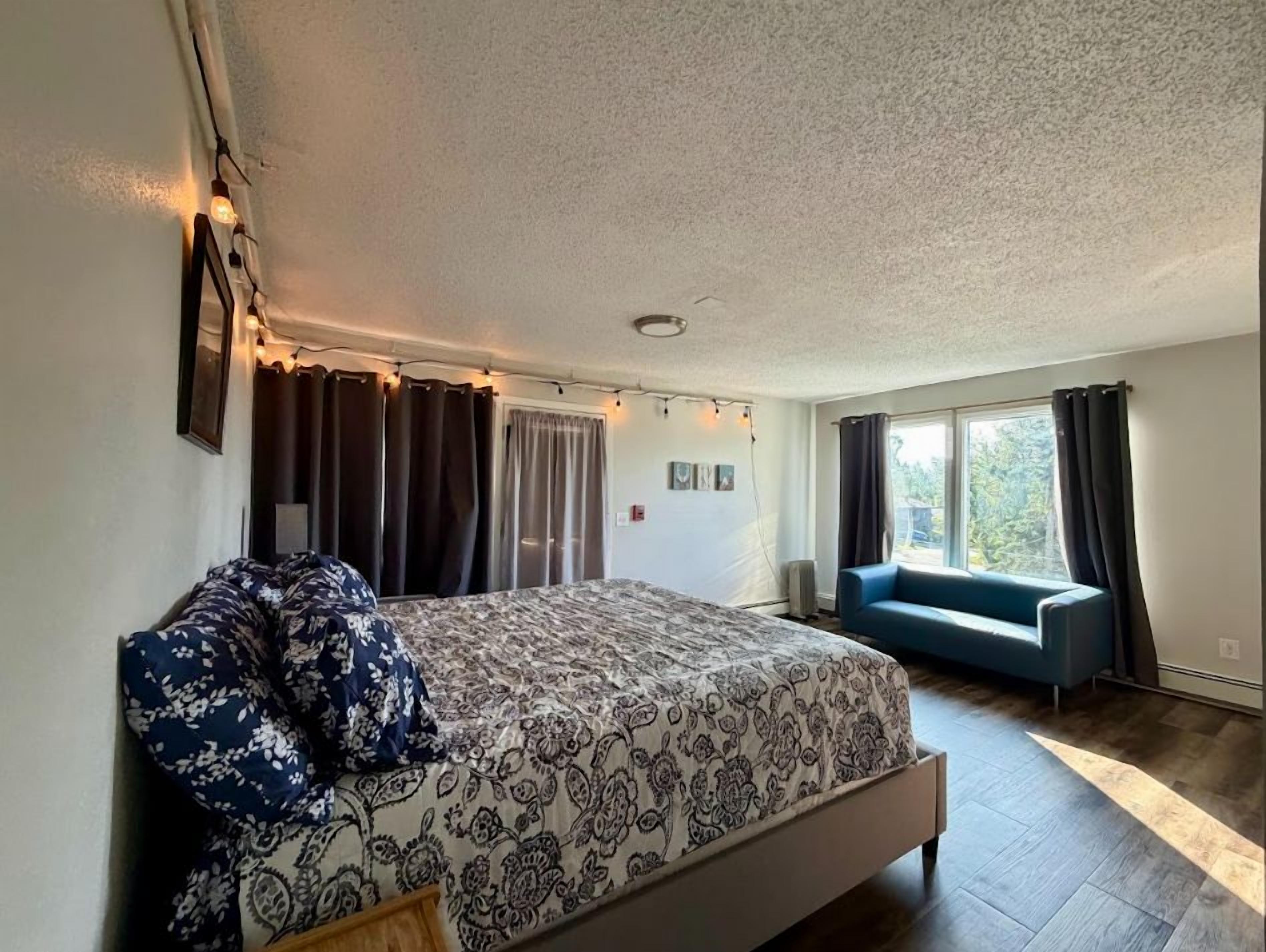 Quarto com cama, sofá, janela e luminária no teto.