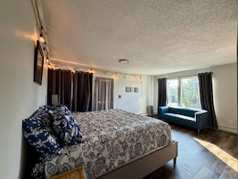 Quarto com cama, sofá, janela e luminária no teto.