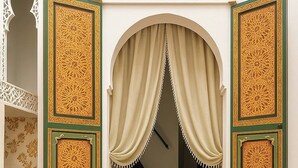 Uma porta aberta com painéis de madeira elaborados e um chão de azulejos que dá acesso a uma escadaria.