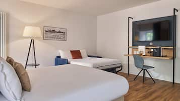 Quarto de hotel com duas camas, uma escrivaninha, televisão de tela plana, luminária e um quadro na parede.