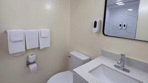 A modern bathroom with a toilet, sink, and towel dispenser.