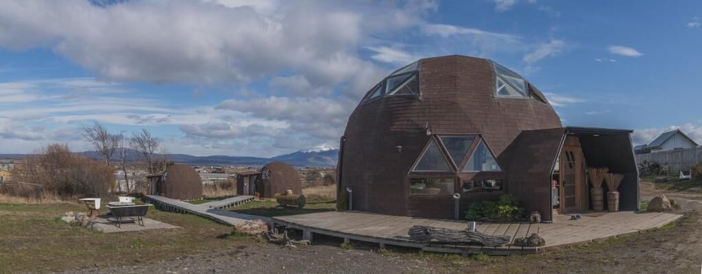 Um edifício em forma de cúpula com telhado plano, janelas grandes e um deque de madeira.