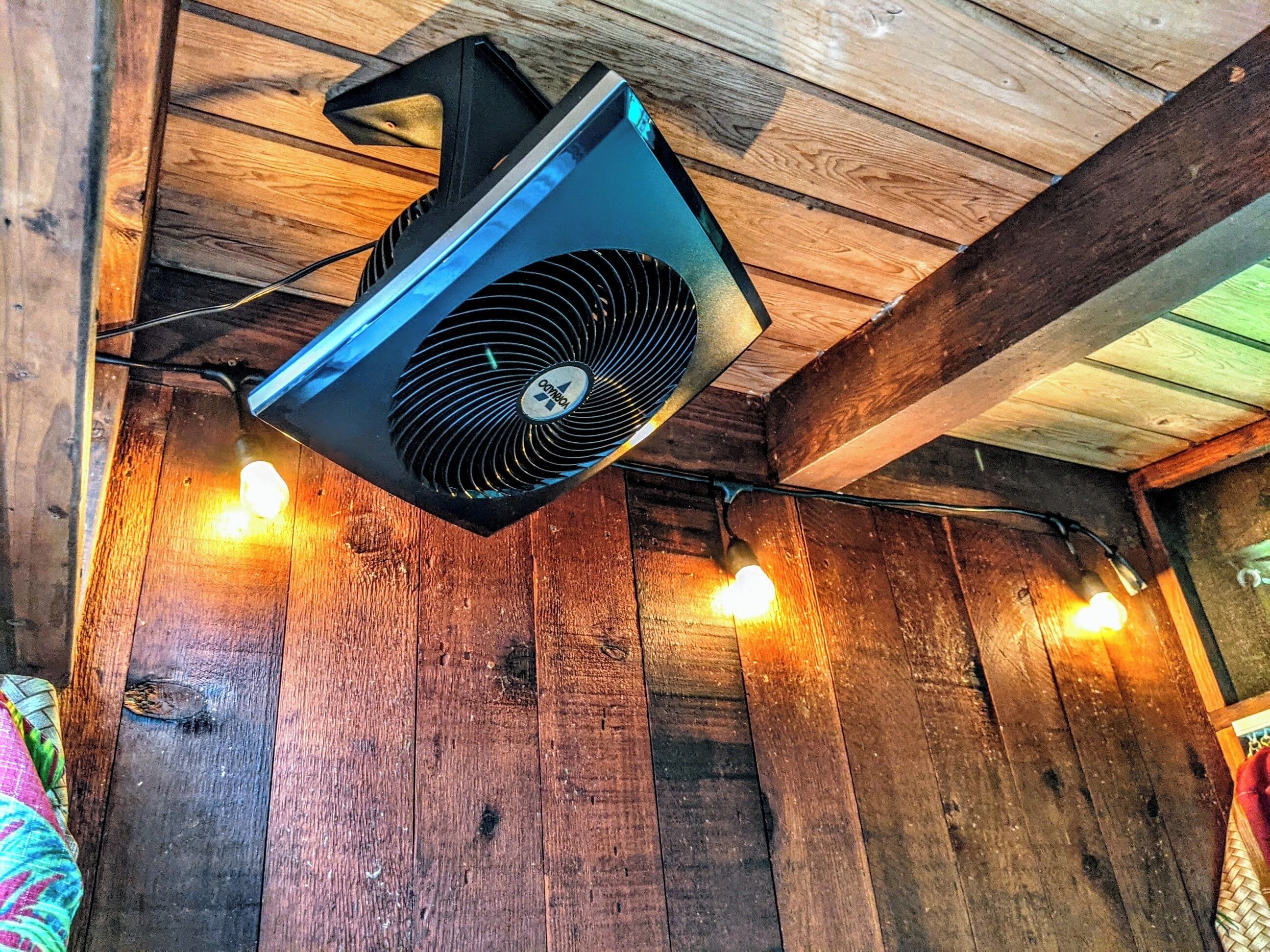 Um projetor fixado no teto em um quarto rústico de madeira, com vigas aparentes e luzes de cordão.