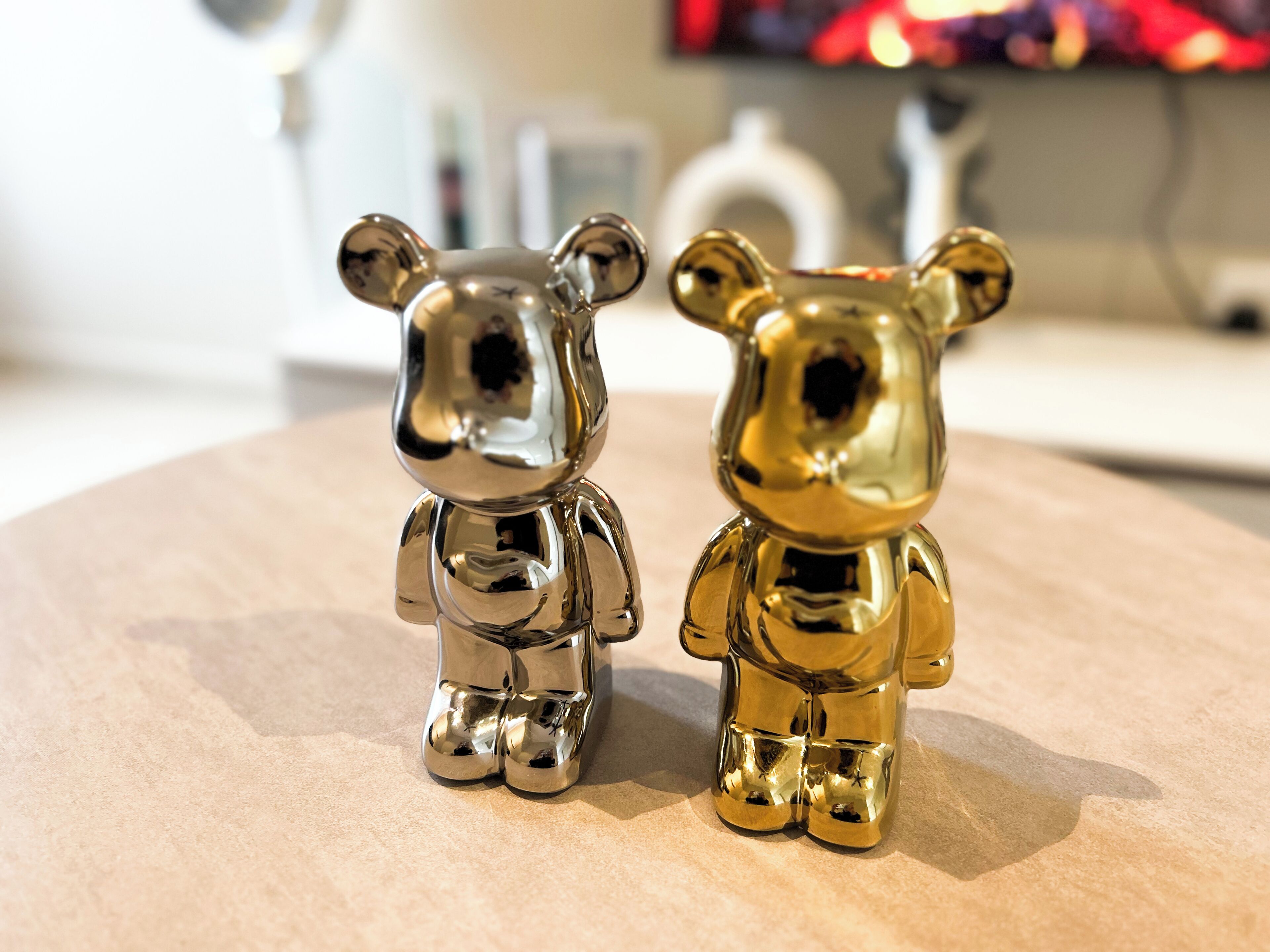 Duas figuras de urso metálicas sobre uma superfície de madeira.