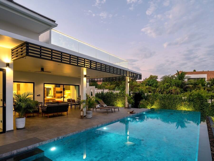 Uma casa moderna com piscina, área de estar externa e um espaço coberto para relaxar.