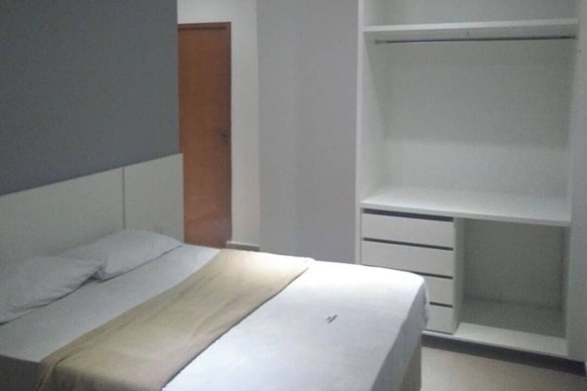 Um quarto com uma cama, um guarda-roupa e uma porta.