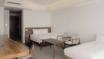 Quarto de hotel com duas camas, uma mesa de madeira e duas cadeiras.