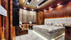 Quarto com uma cama grande, um banco e uma mesinha.