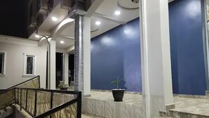 Um saguão de hotel com piso de mármore, escadaria e parede azul decorativa.