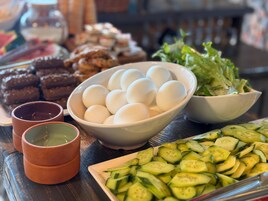 Uma mesa com diversos alimentos, incluindo ovos, pepinos e produtos de panificação.