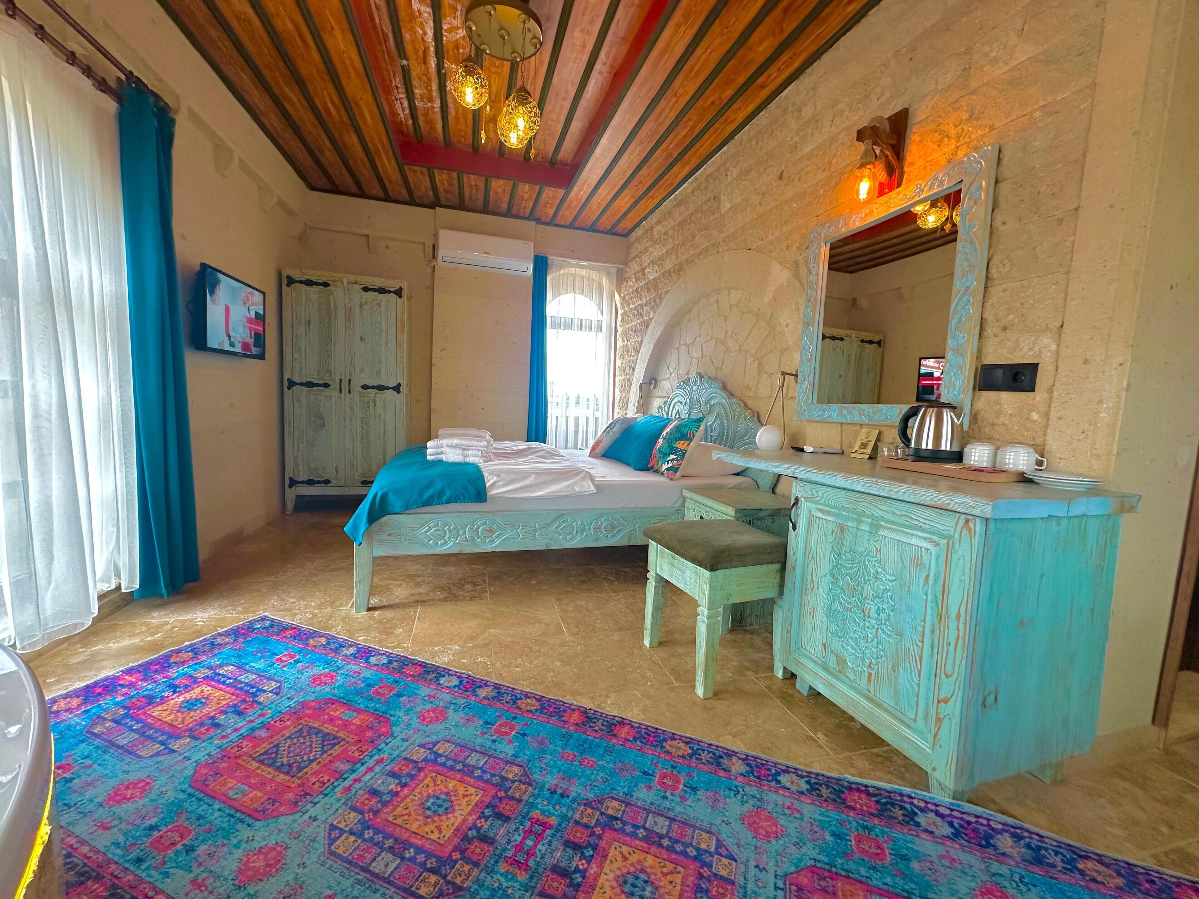 Um quarto com cama, penteadeira, espelho e um tapete colorido.