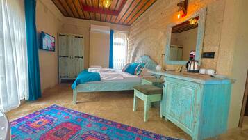 Um quarto com cama, penteadeira, espelho e um tapete colorido.