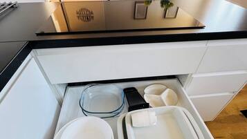 Uma cozinha com bancada preta, armários brancos e piso de madeira.