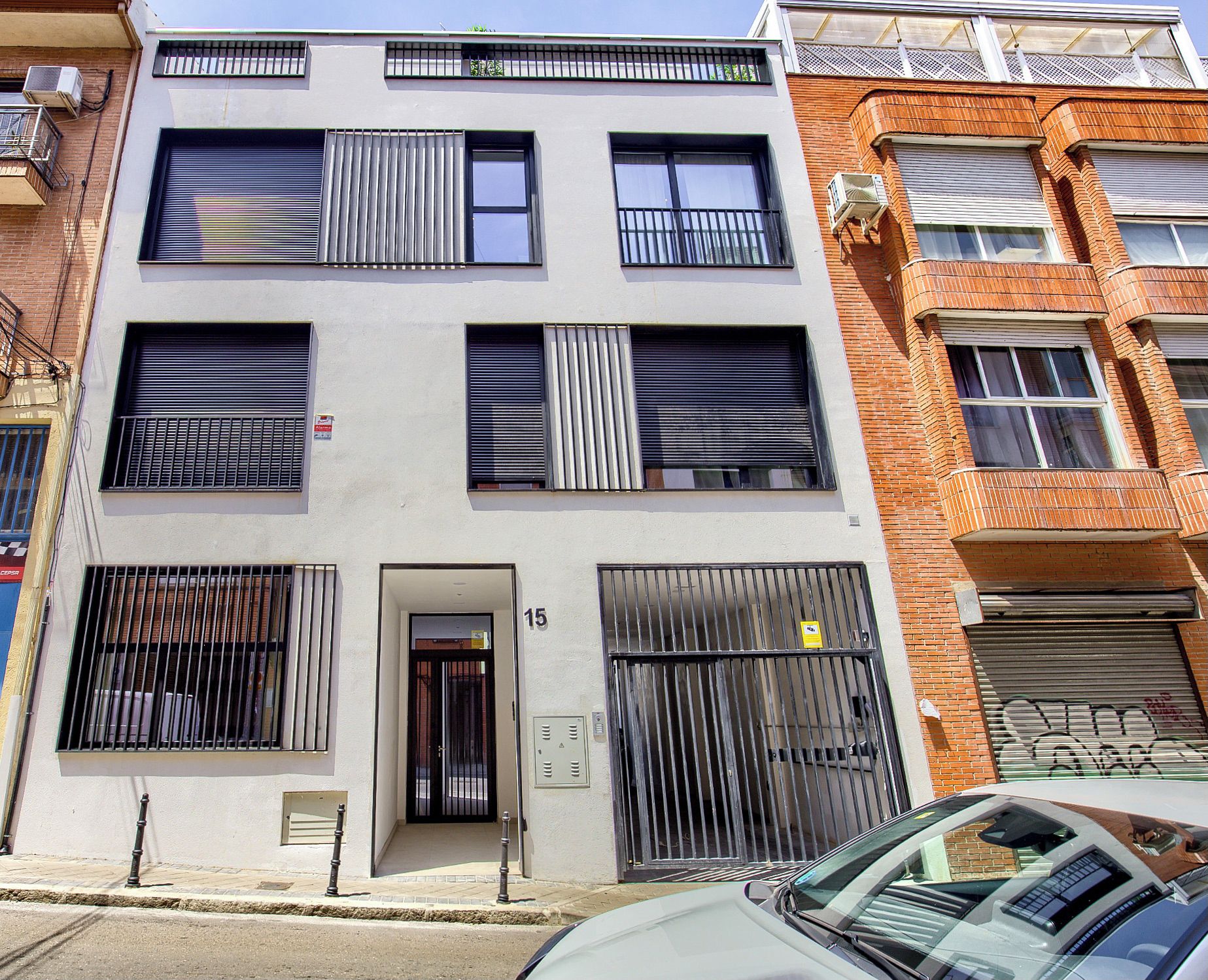 Edifício de vários andares com entrada no nível da rua, número 15, e porta de garagem.