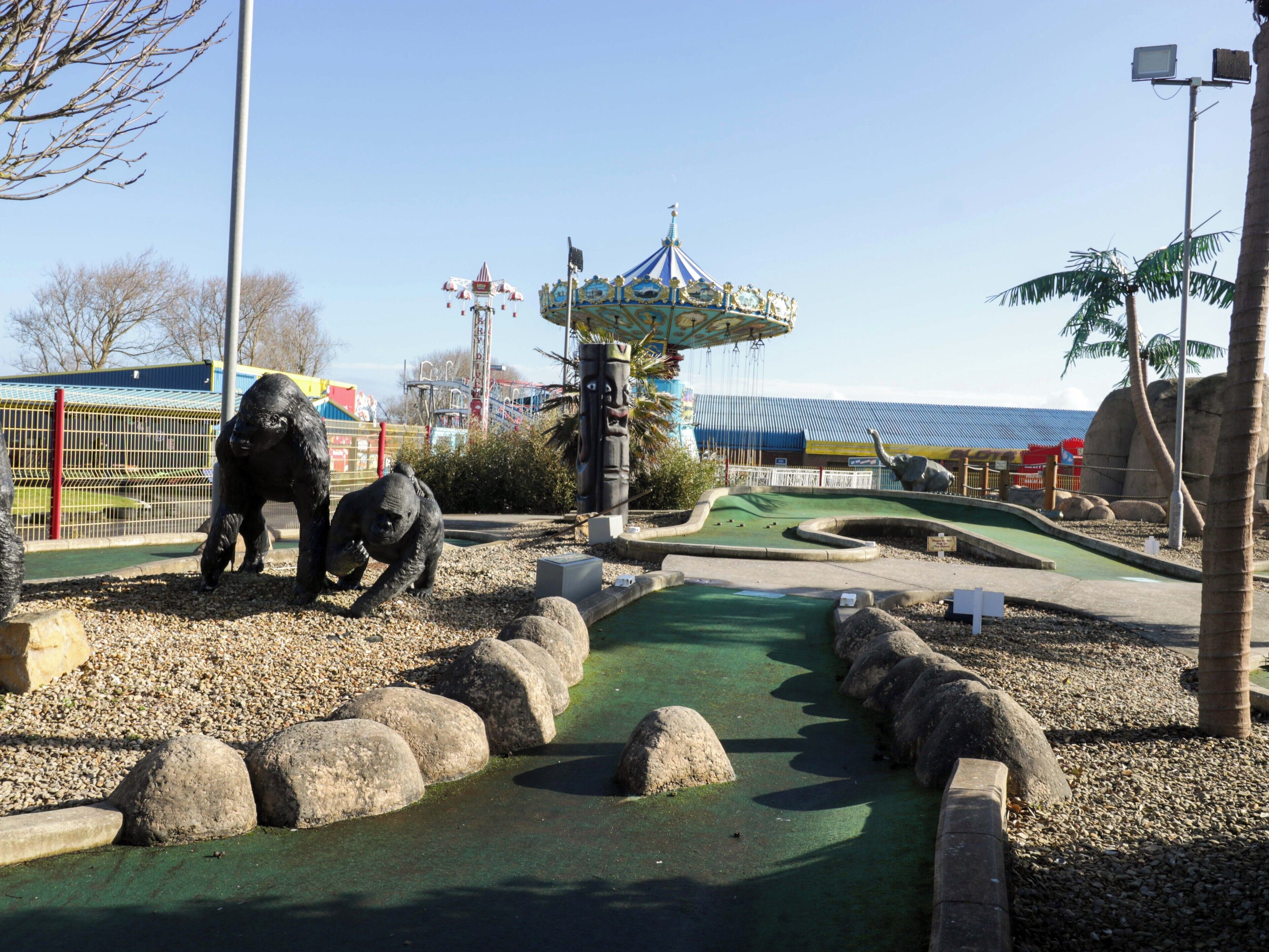 Um campo de minigolfe com carrossel e uma estátua de gorila.