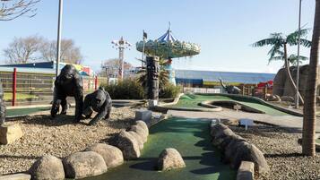 Um campo de minigolfe com carrossel e uma estátua de gorila.