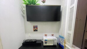 Uma cozinha compacta com bancada preta, micro-ondas e uma pia pequena.