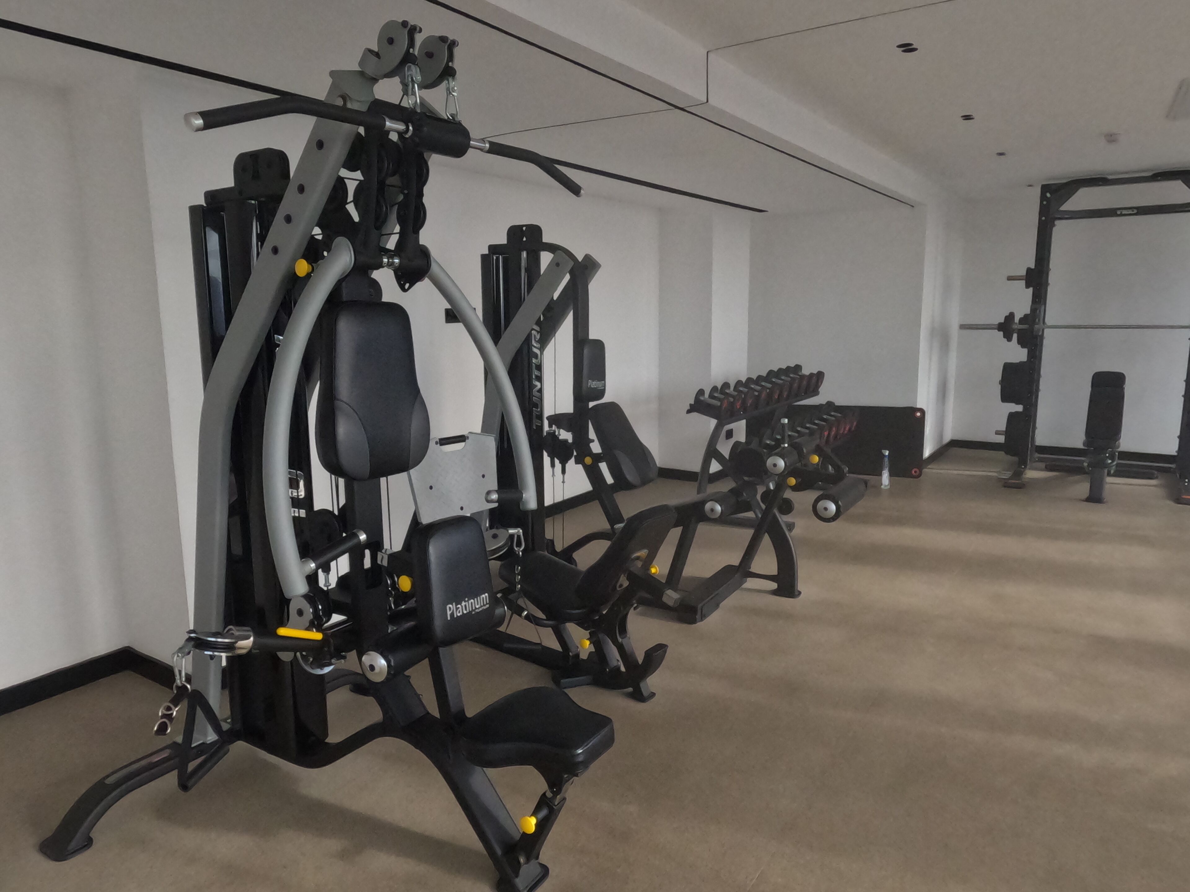 Uma academia com diversos equipamentos de exercícios, incluindo uma prensa de pernas e uma prensa de peito.
