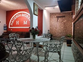 Uma área de refeições com uma mesa redonda e cadeiras, uma parede vermelha com um logotipo e uma parede de pedra.