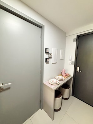 Casa de banho pequena e limpa, com sanita, lavatório e espelho. Três caixas de lixo estão dispostas sob o lavatório, e uma porta com puxador.