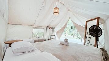 Alojamento em tenda com duas camas, uma luminária pendente e um ventilador.